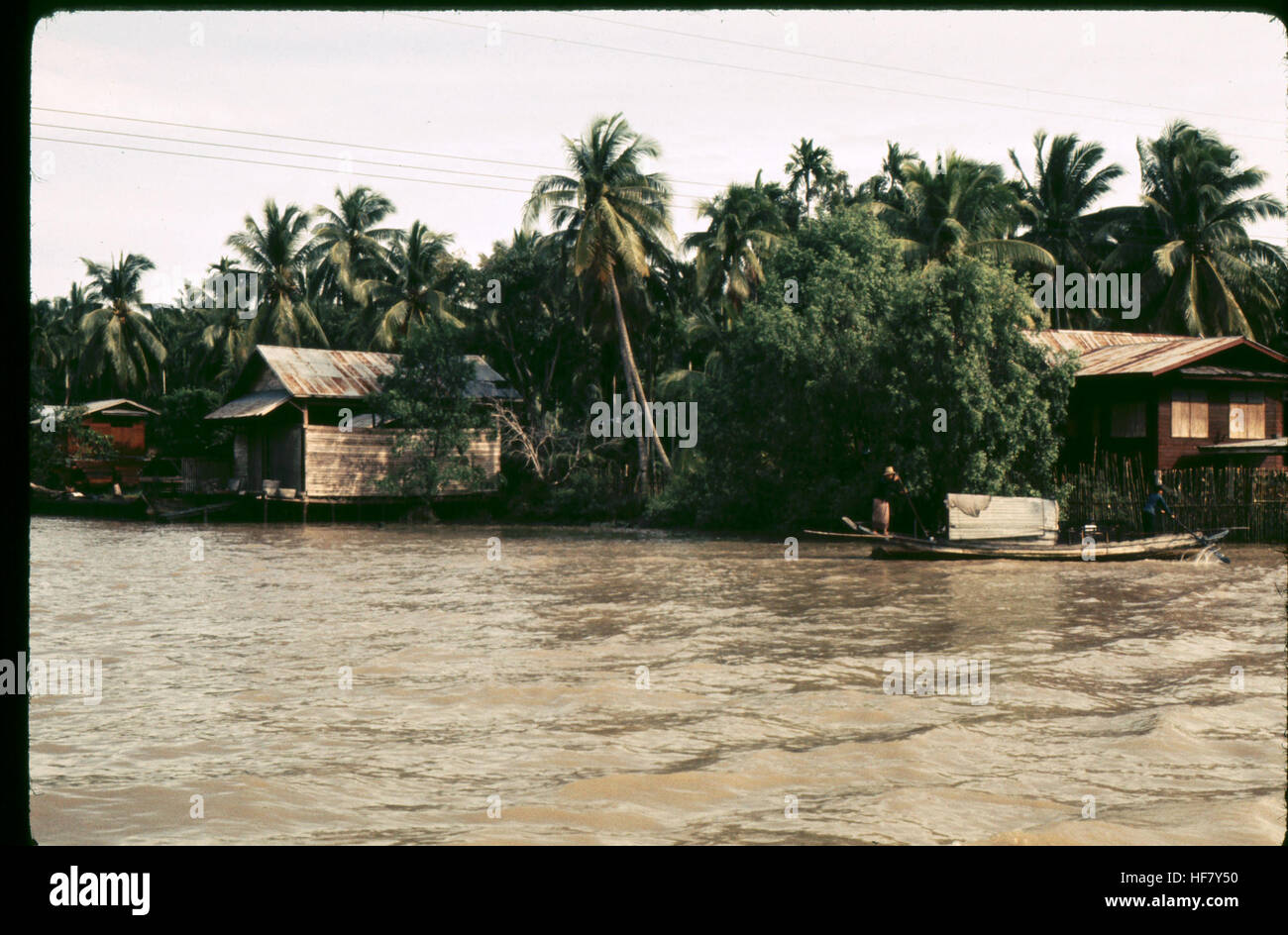 A sampan boat is shown traveling through a canal in Bangkok, Thailand ...