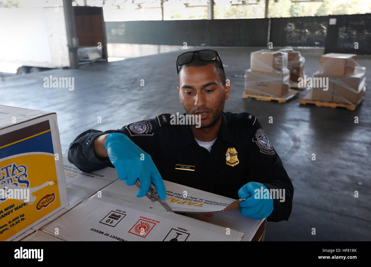 A U.S. Customs and Border Protection officer uses a knife to cut open a ...