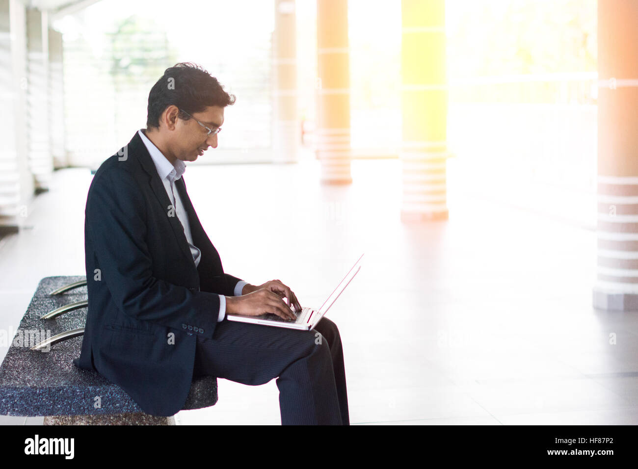 Asian Indian businessman using laptop computer while waiting train at ...