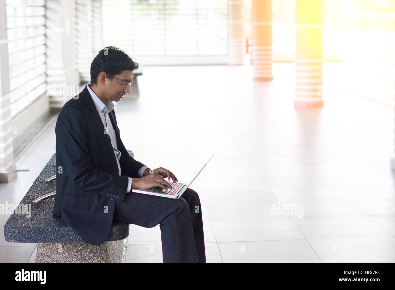Asian Indian businessman using laptop computer while waiting train at ...