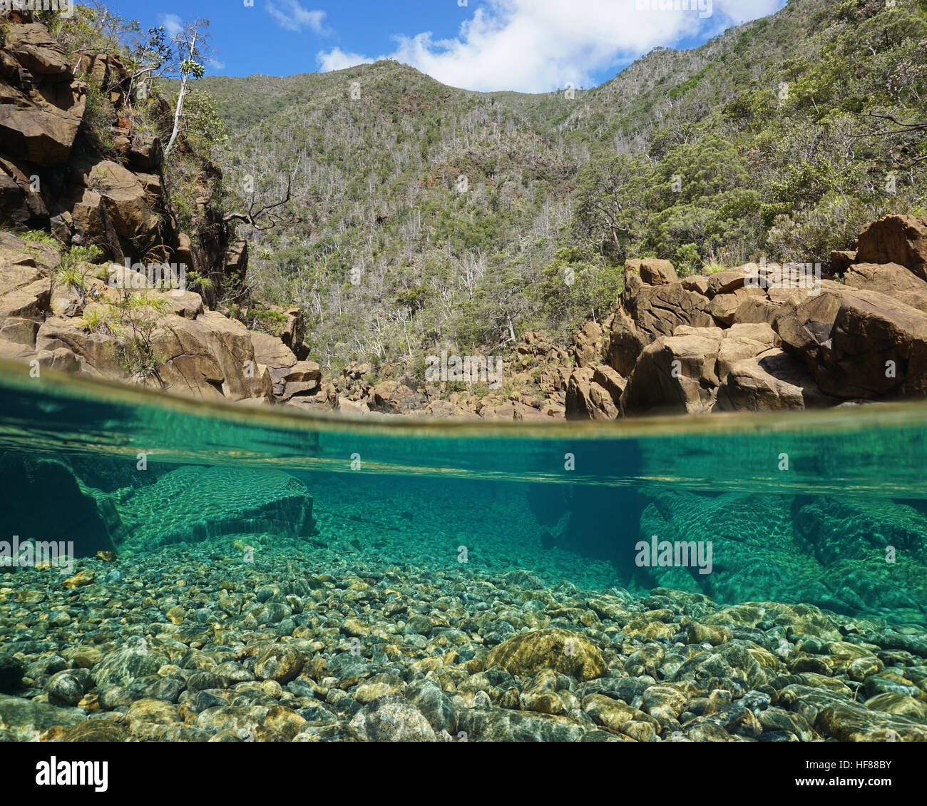 River split view over and under the water with pebbles on the riverbed ...