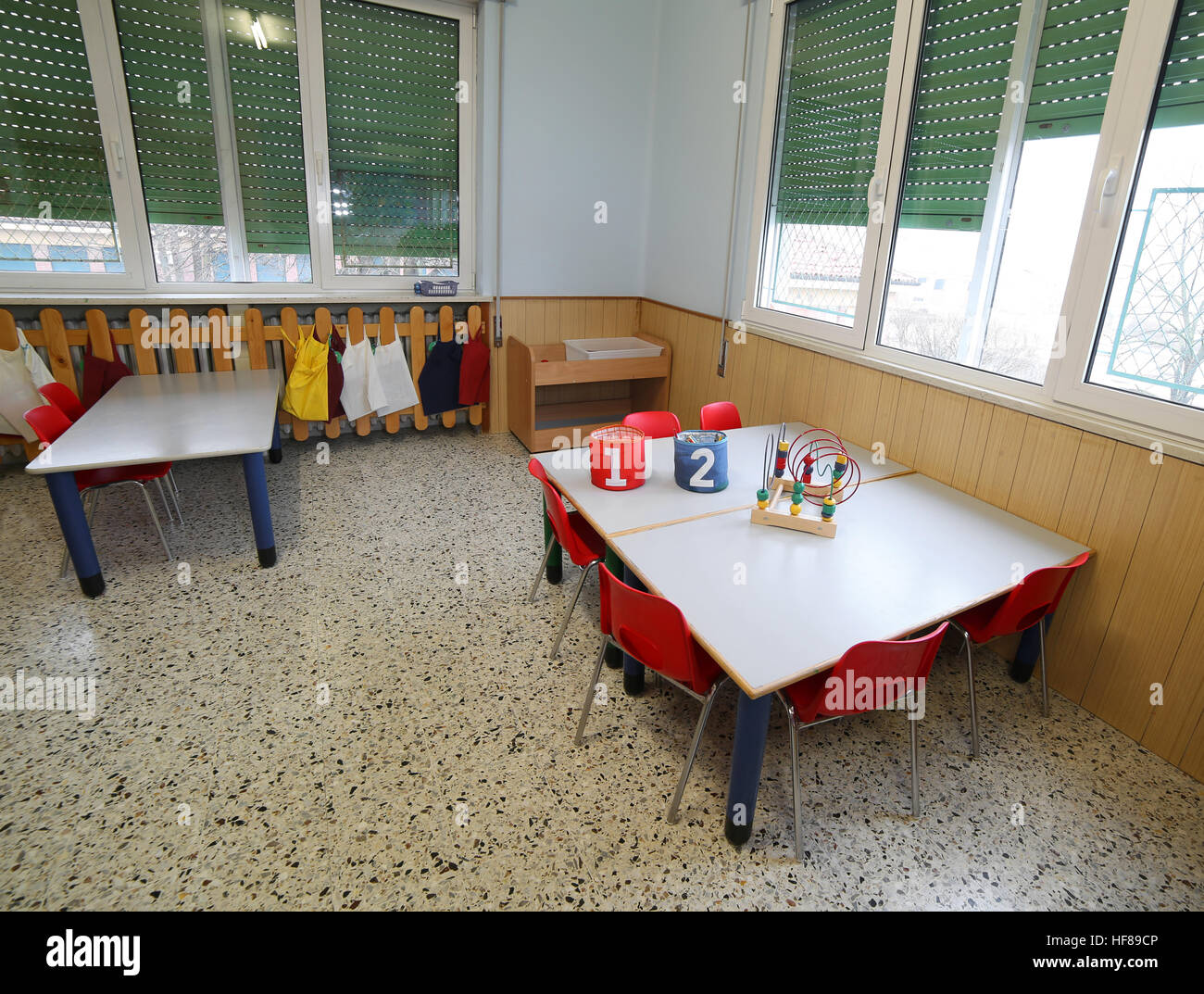 inside of a classroom with small red chairs and benches and some toys ...
