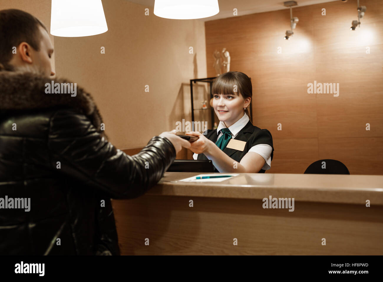 Pretty hotel receptionist giving key to male guest Stock Photo - Alamy