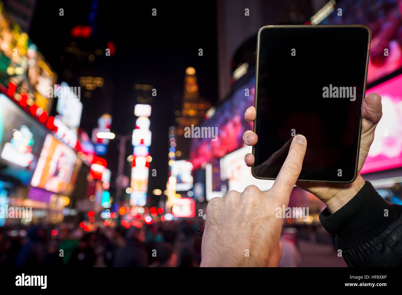 Hand touching the blank screen of a tablet in Times Square, New York ...