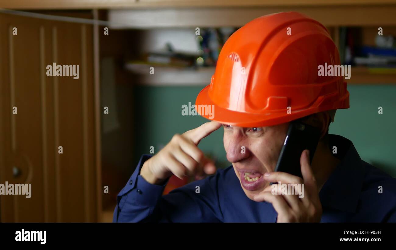 angry man construction worker in a hardhat shouting, talking on phone ...