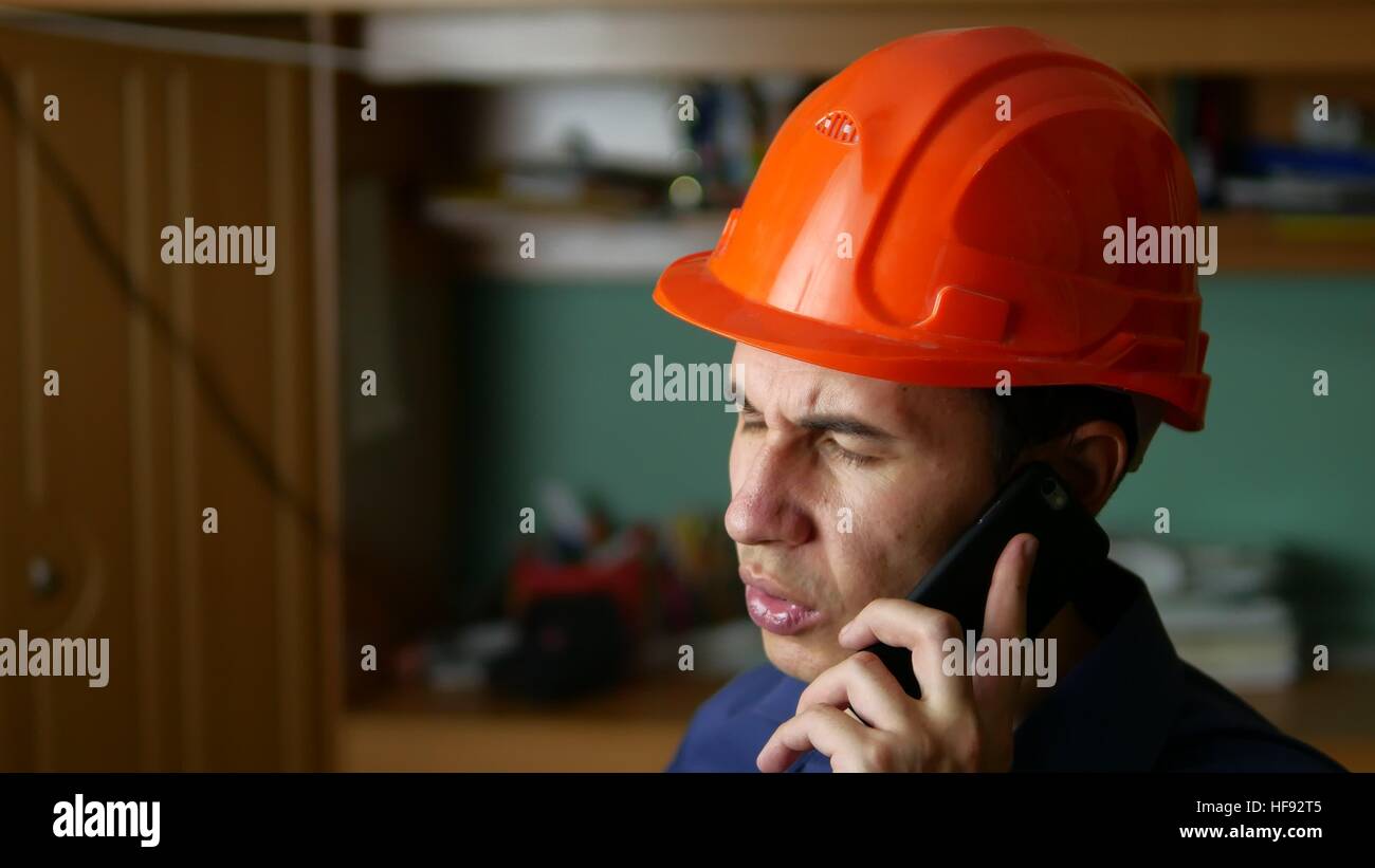 angry man construction worker in a hardhat shouting, talking on the ...