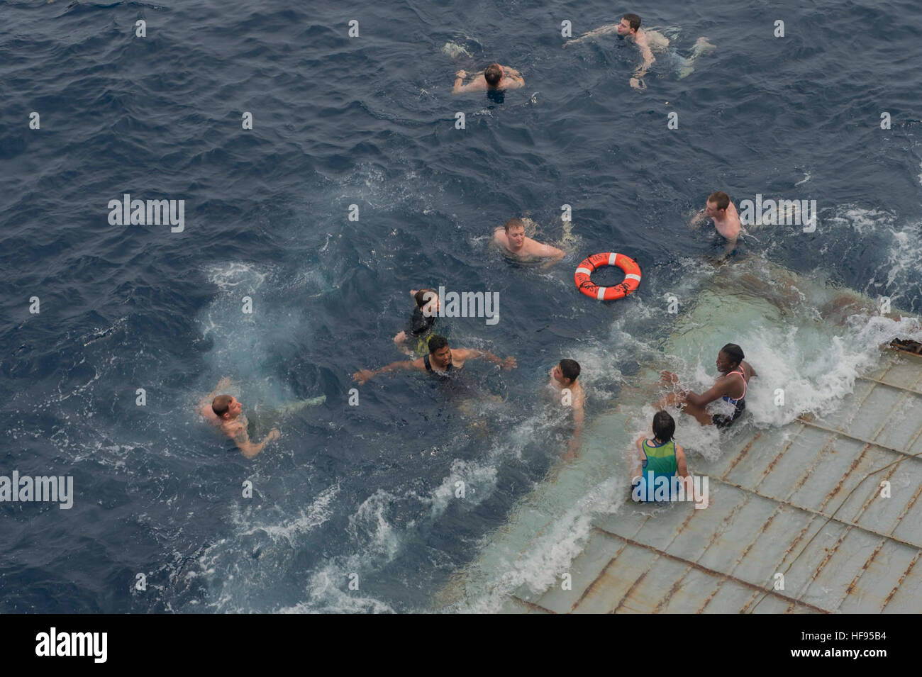 U.S. Sailors swim off the stern gate of the dock landing ship USS ...