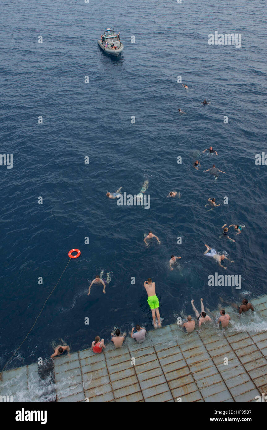 U.S. Sailors and Marines swim off the stern gate of the dock landing ...