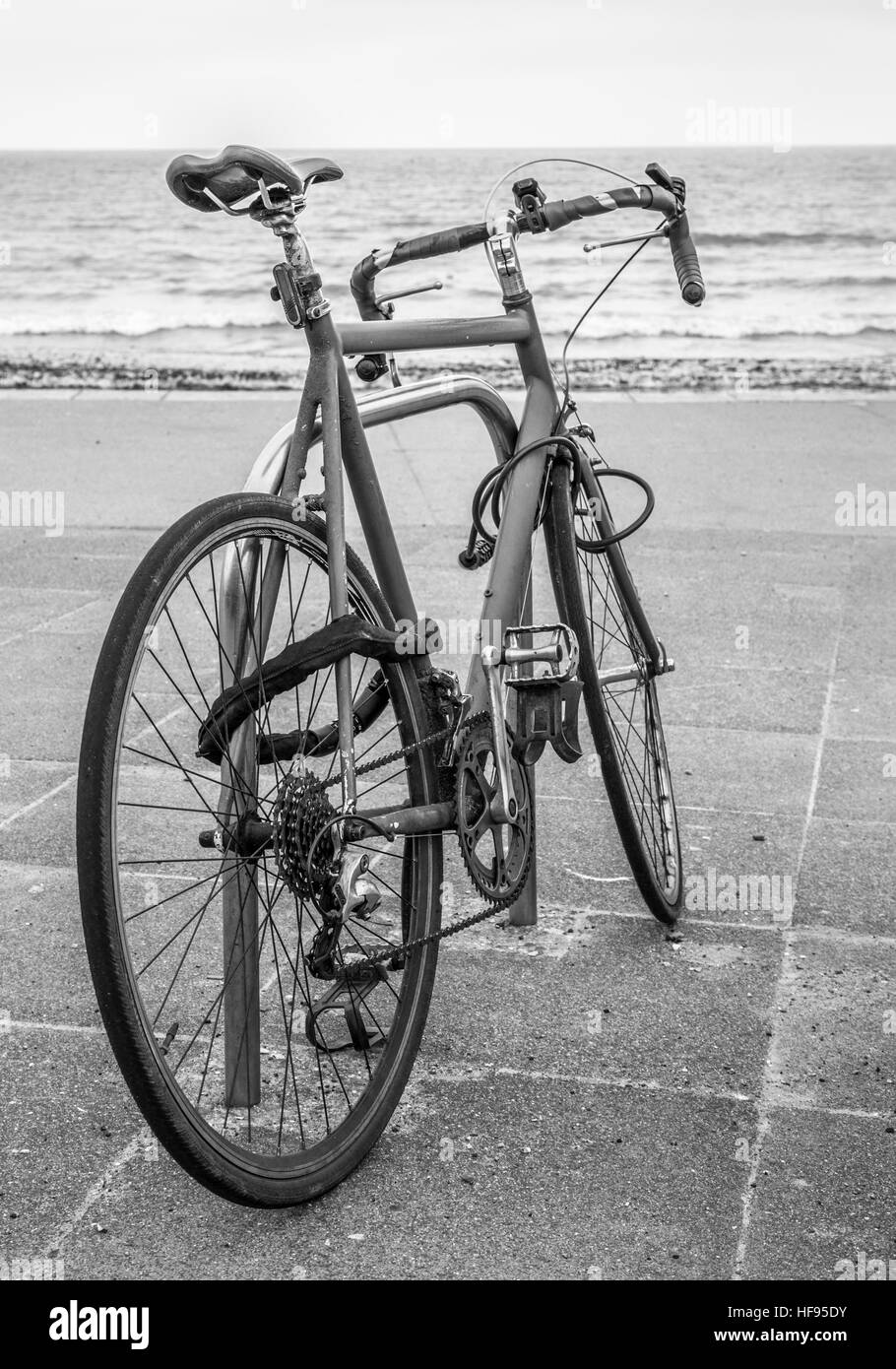 bicycle at seaside chained up on bole rack Stock Photo - Alamy