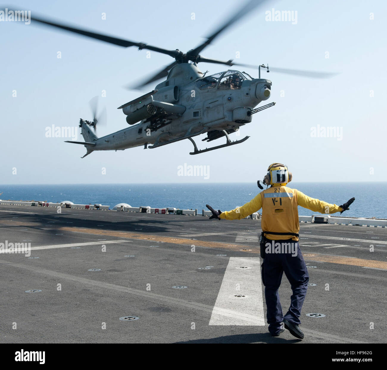 An aircraft handler signals to an AH-1Z Cobra helicopter assigned to ...