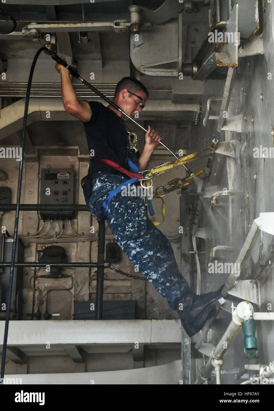 U.S. Navy Seaman Jeremy McGraw uses a pressure washer to clean a ...