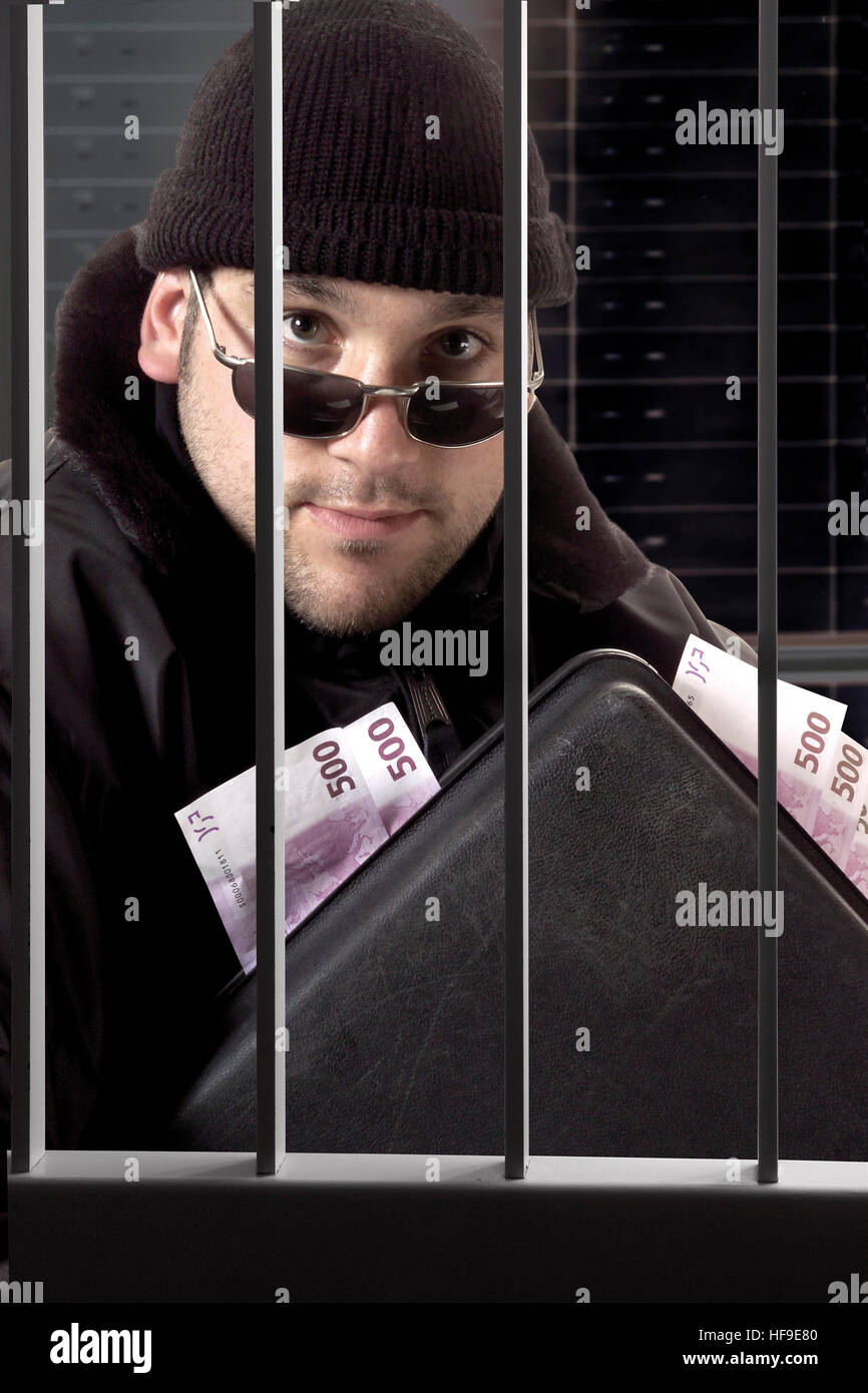 Burglar in a vault carrying a briefcase stuffed with cash Stock Photo ...