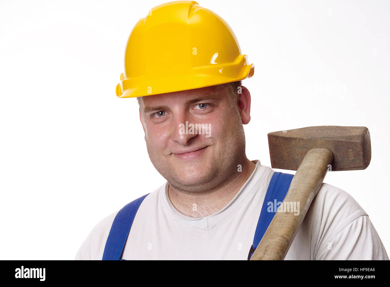 Construction worker wearing yellow hardhat holding a hammer over his ...