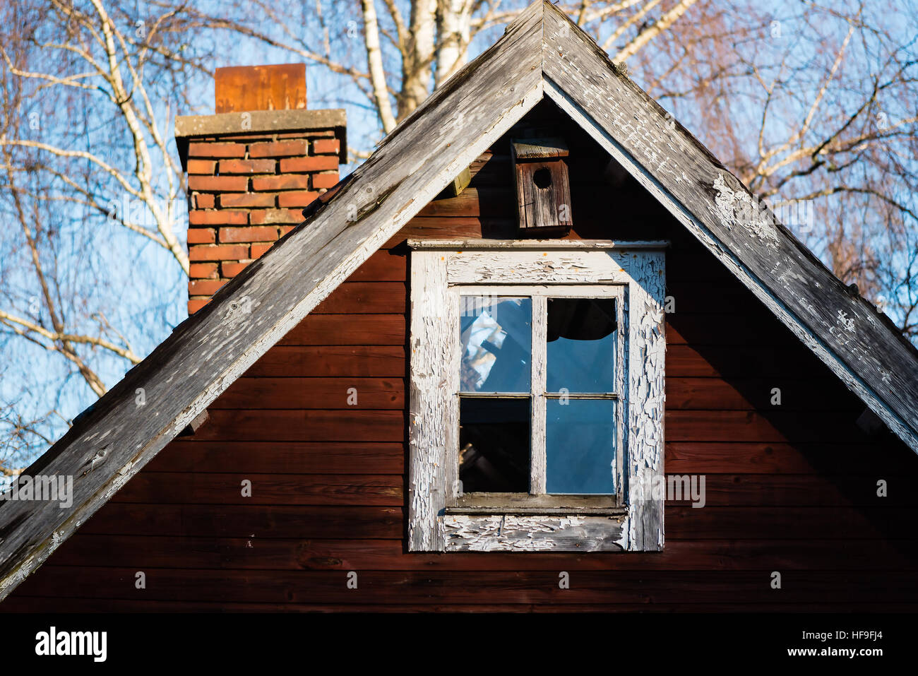 Broken window on an old red wooden house. Birdhouse or nesting box ...