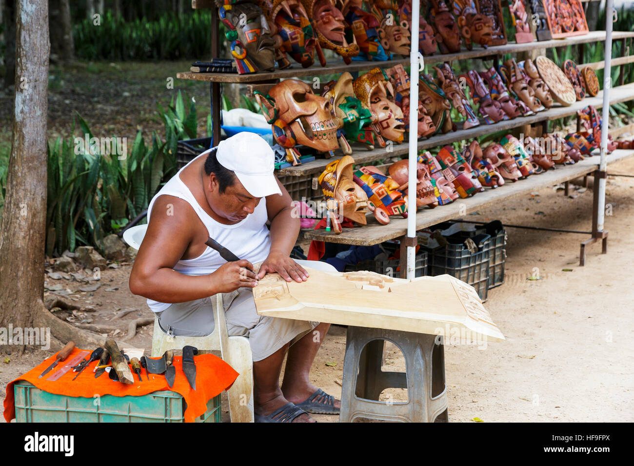 Man hand carving a traditional Mayan scene from wood, to sell at his ...
