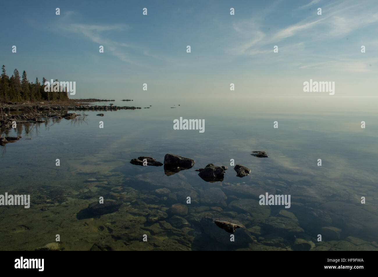 Dead calm afternoon image of clear lake huron water and limestone rocks ...