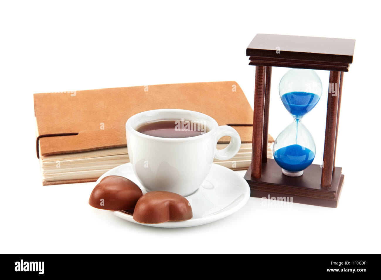 hourglass tea cup and a book on a white background Stock Photo - Alamy