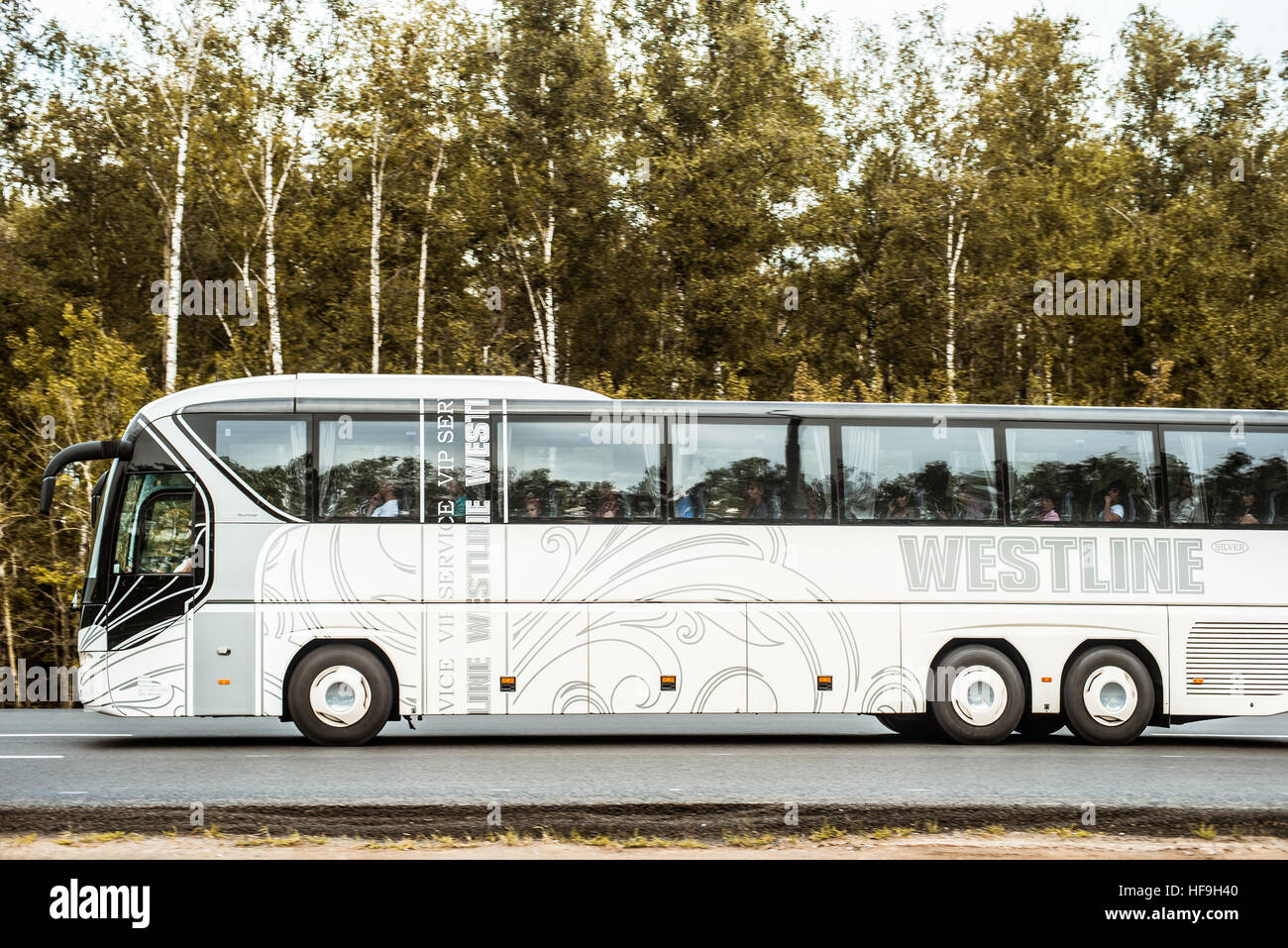 touring bus with passengers goes along a forest road Stock Photo - Alamy