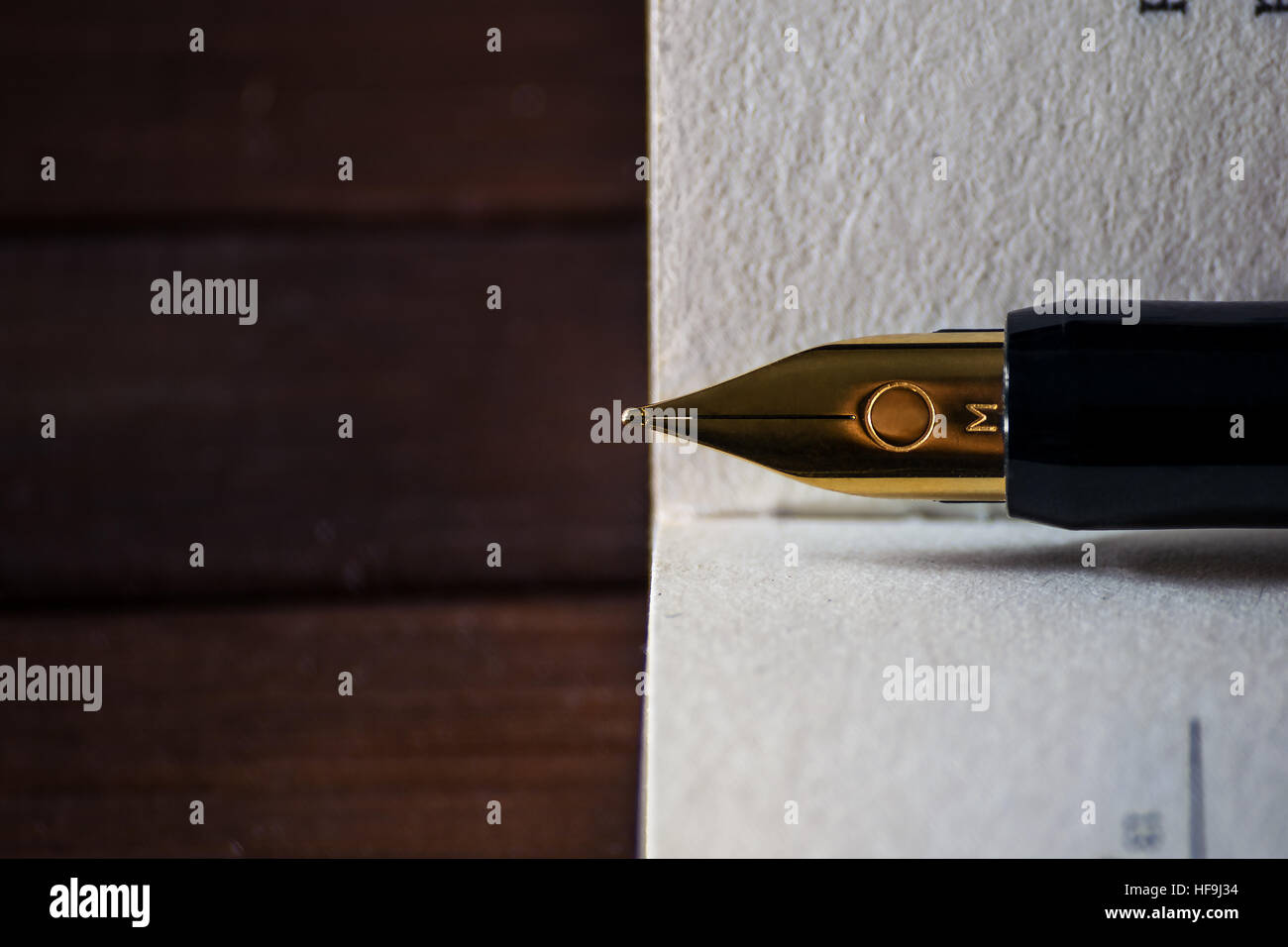 Close-up of golden fountain-pen on open book with wooden background ...