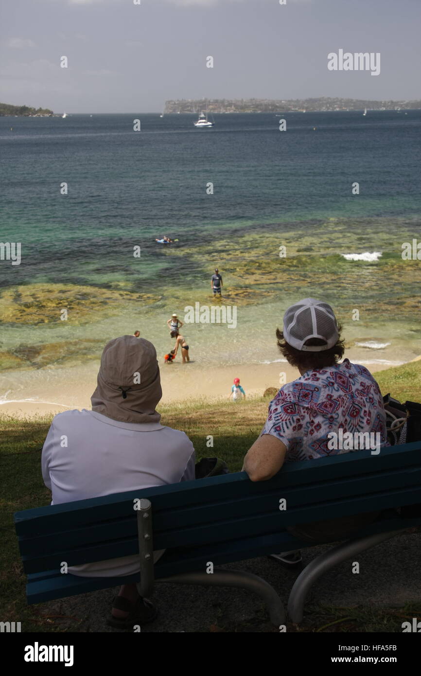 Old people watching over children playing in the sea Stock Photo - Alamy