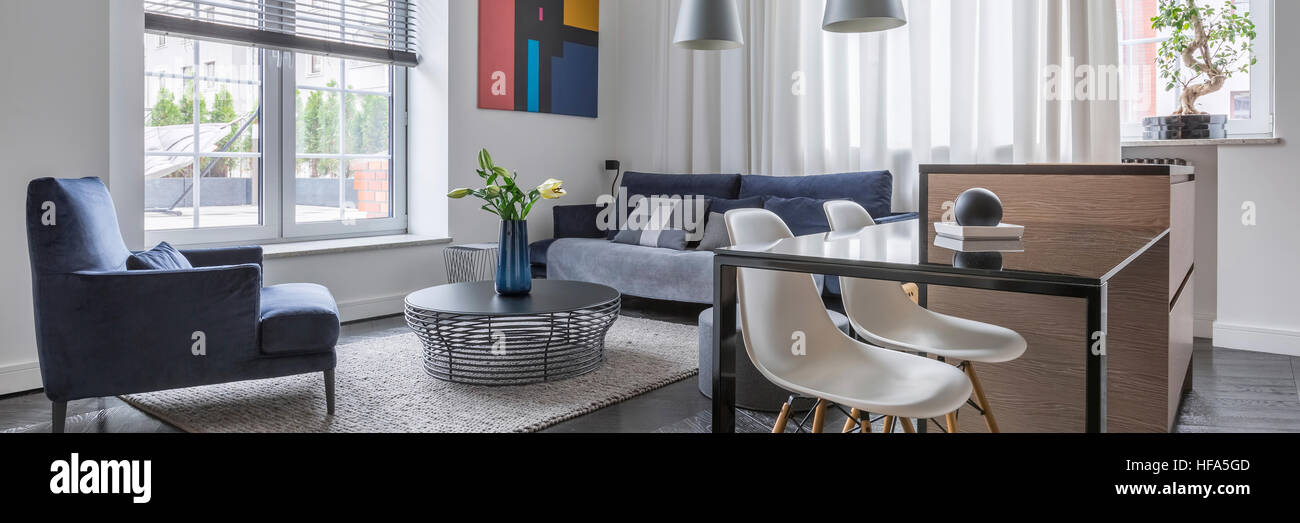 Panorama of loft interior with sofa, armchair, table and big window ...
