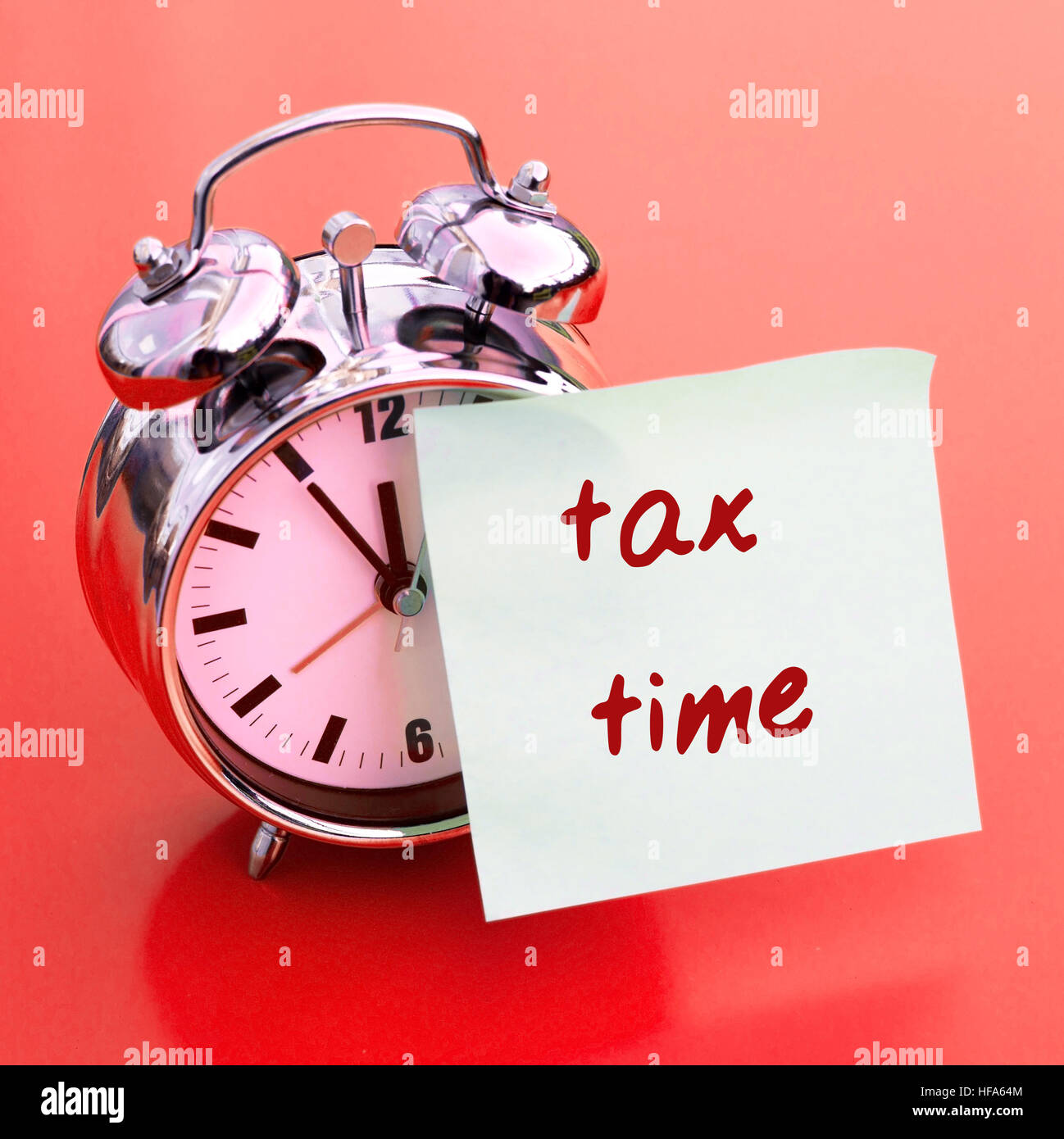 clock on a red table with sticker on it with words Tax Time Stock Photo ...