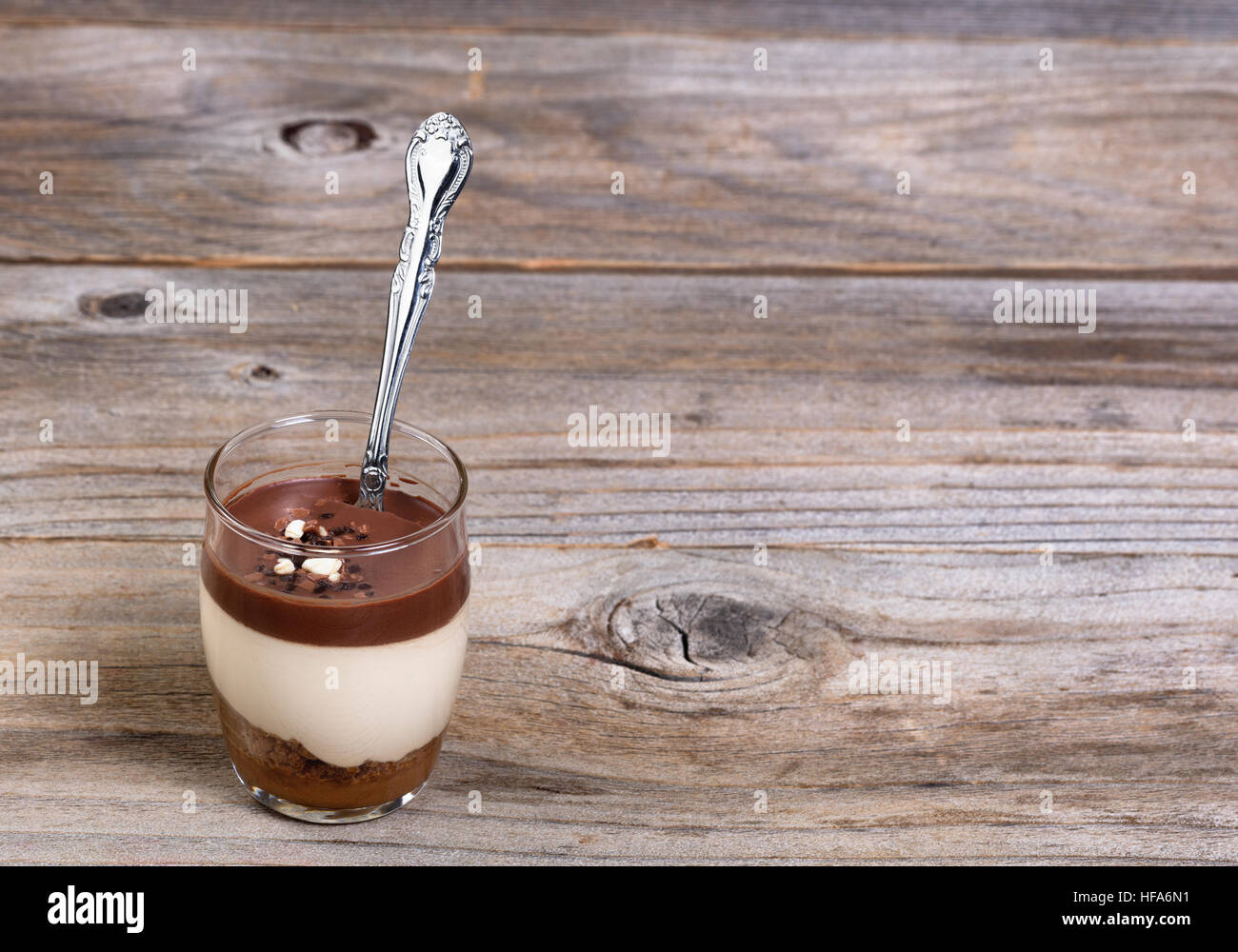 Close up of pudding and cake dessert in glass cup with spoon on rustic ...