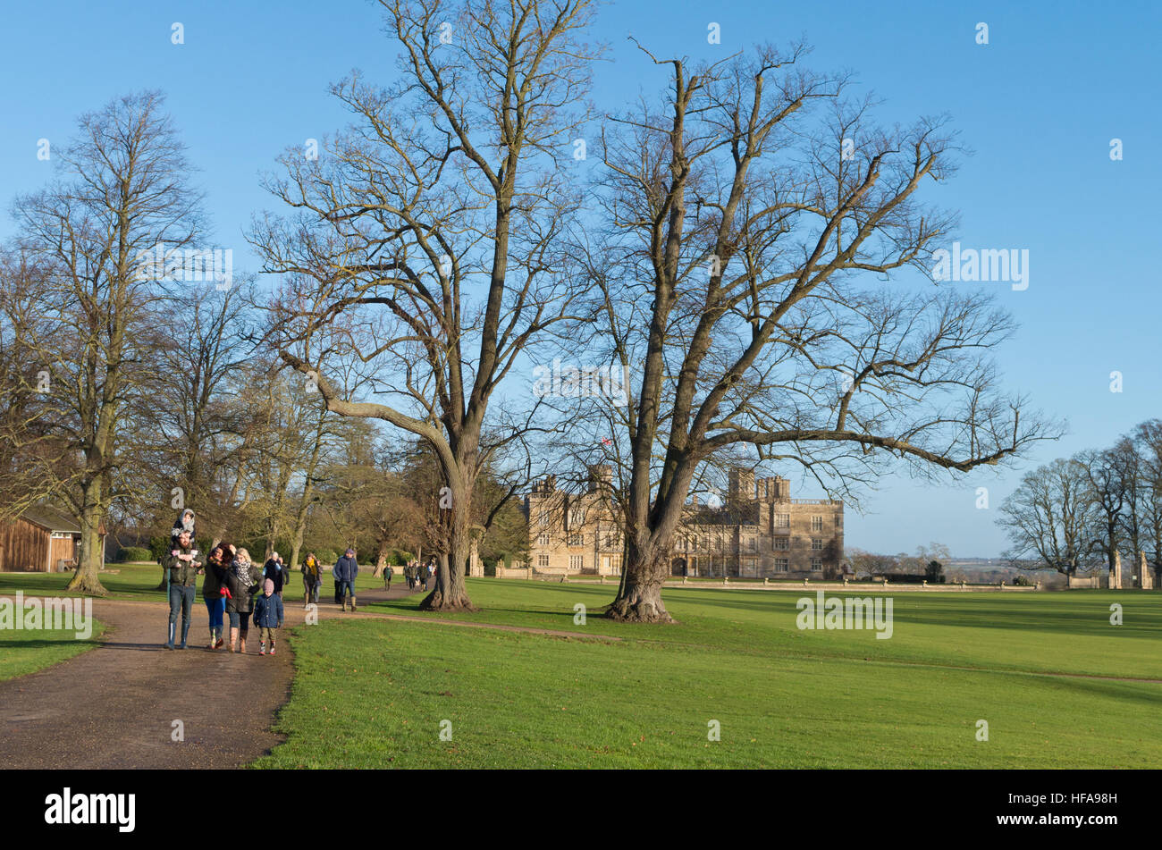 Families walking in the Winter sunshine in the grounds of Castle Ashby ...
