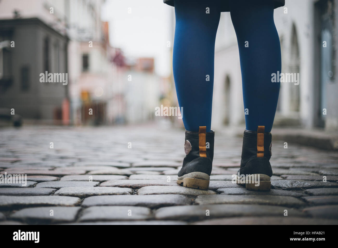 Female legs in trendy boots on cobblestone pavement, from ground back ...
