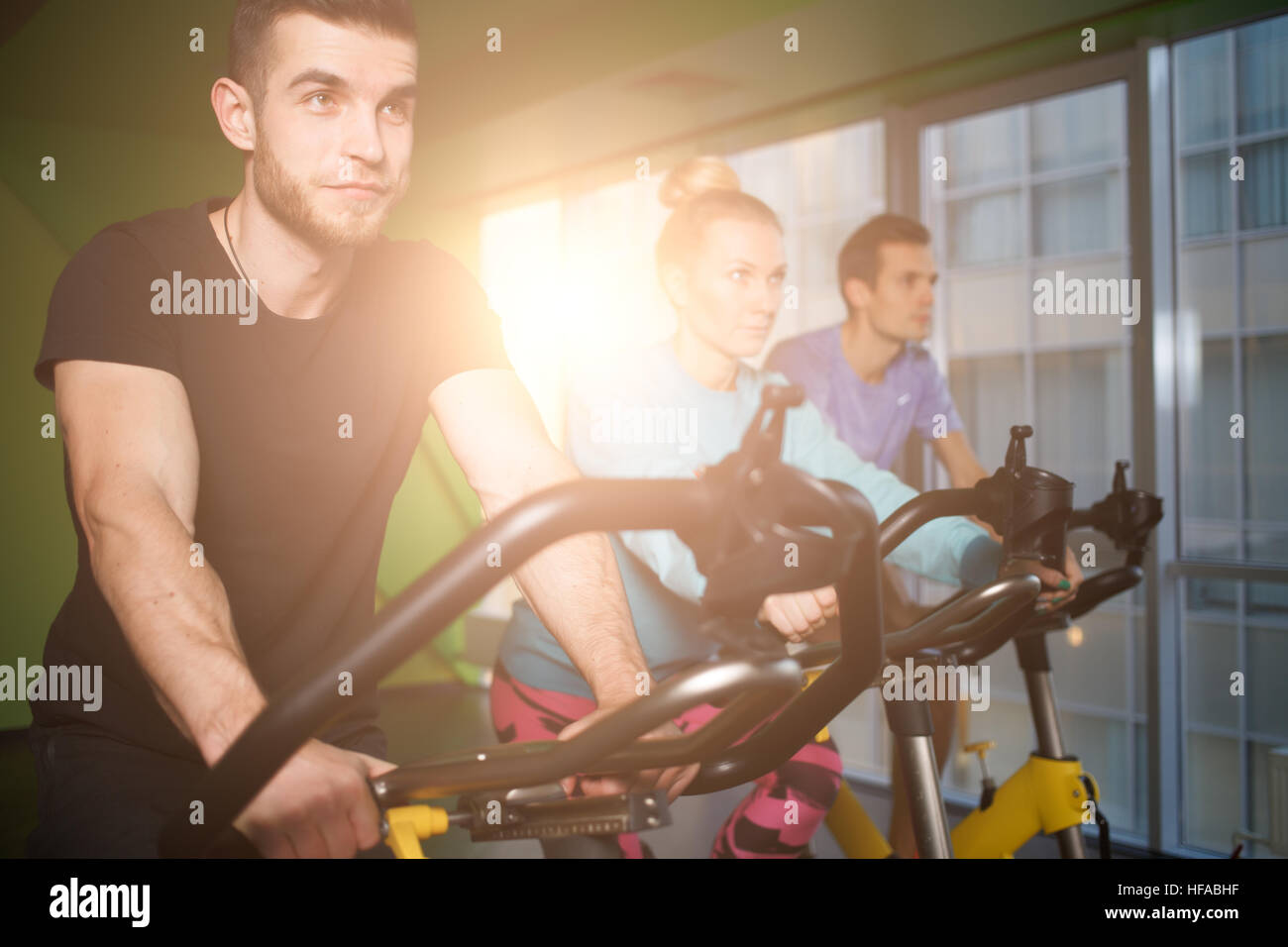 Young people on stationary bike Stock Photo - Alamy