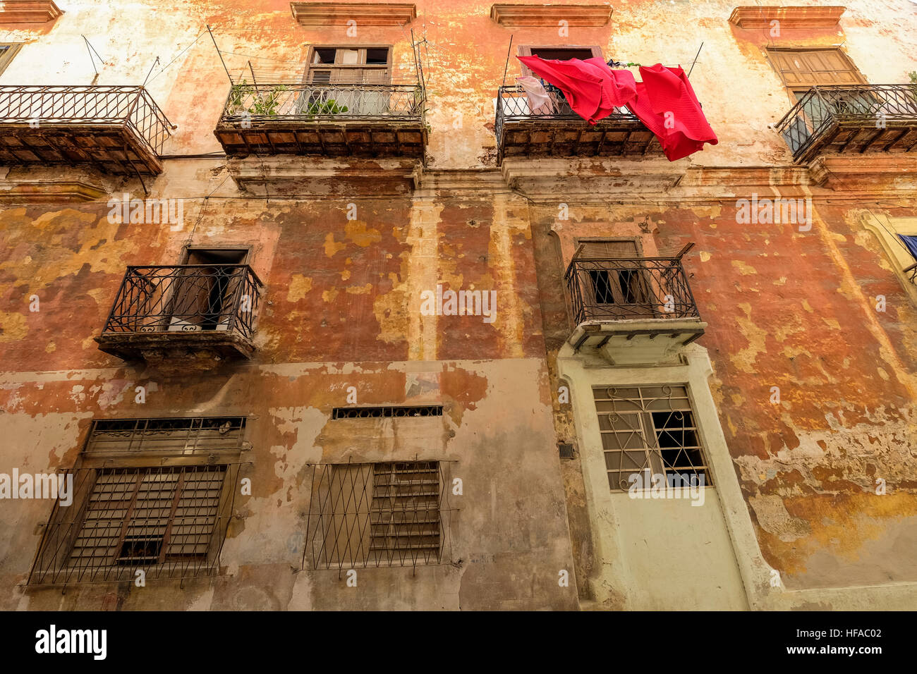 Sandy red coloured old building with red cloths hanging from a high up ...