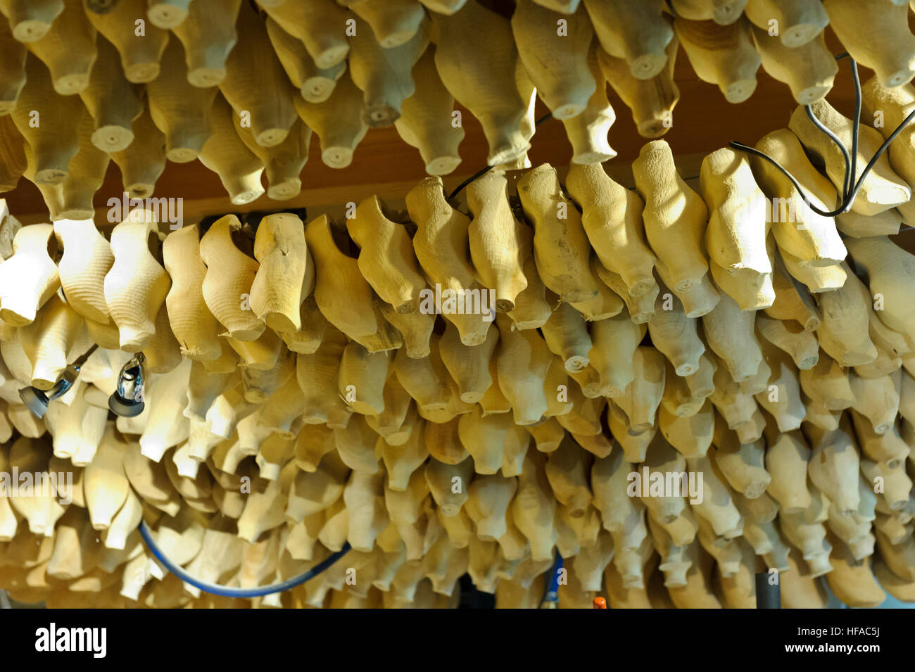 Unfinished wooden clogs hanging from the ceiling in a clogs factory ...