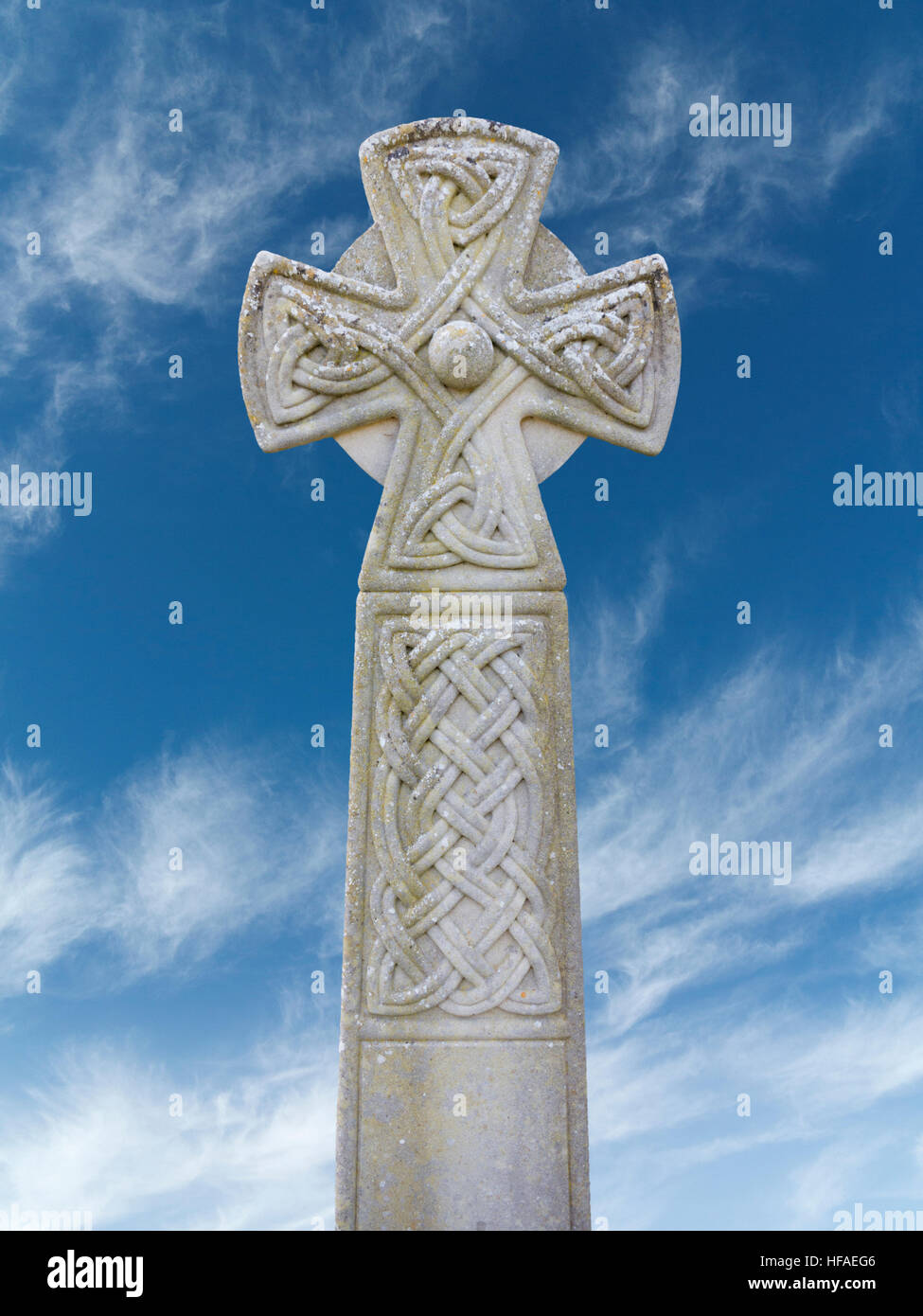 Celtic cross design tall limestone headstone against a blue sky with ...