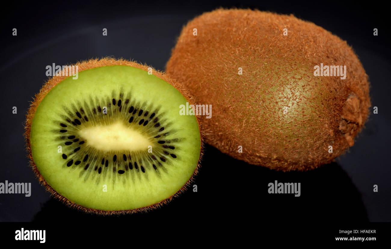 One and half kiwi on the black plate Stock Photo - Alamy
