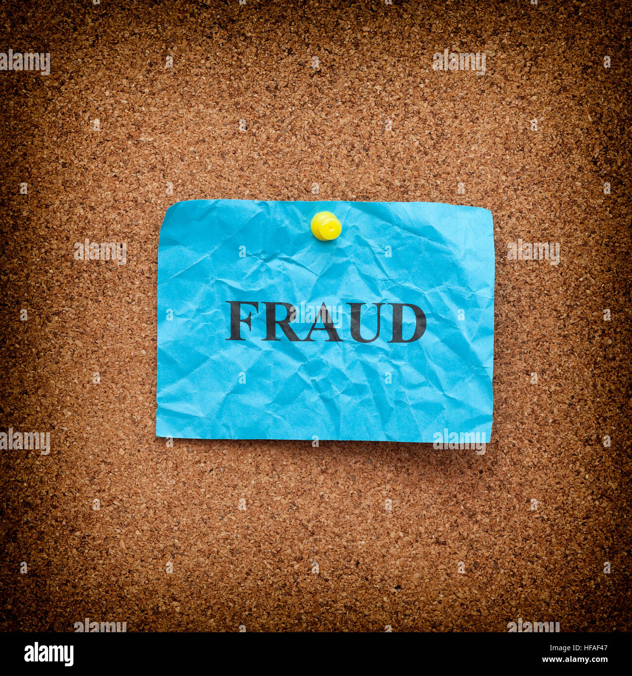Fraud concept. Crumpled blue paper note with the word Fraud on cork ...