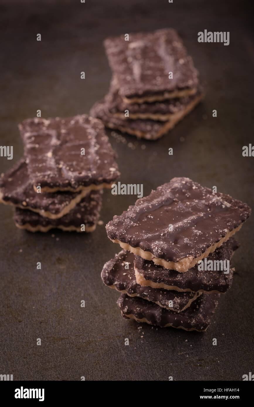 Vertical photo with few stacks of square biscuits with chocolate on one ...