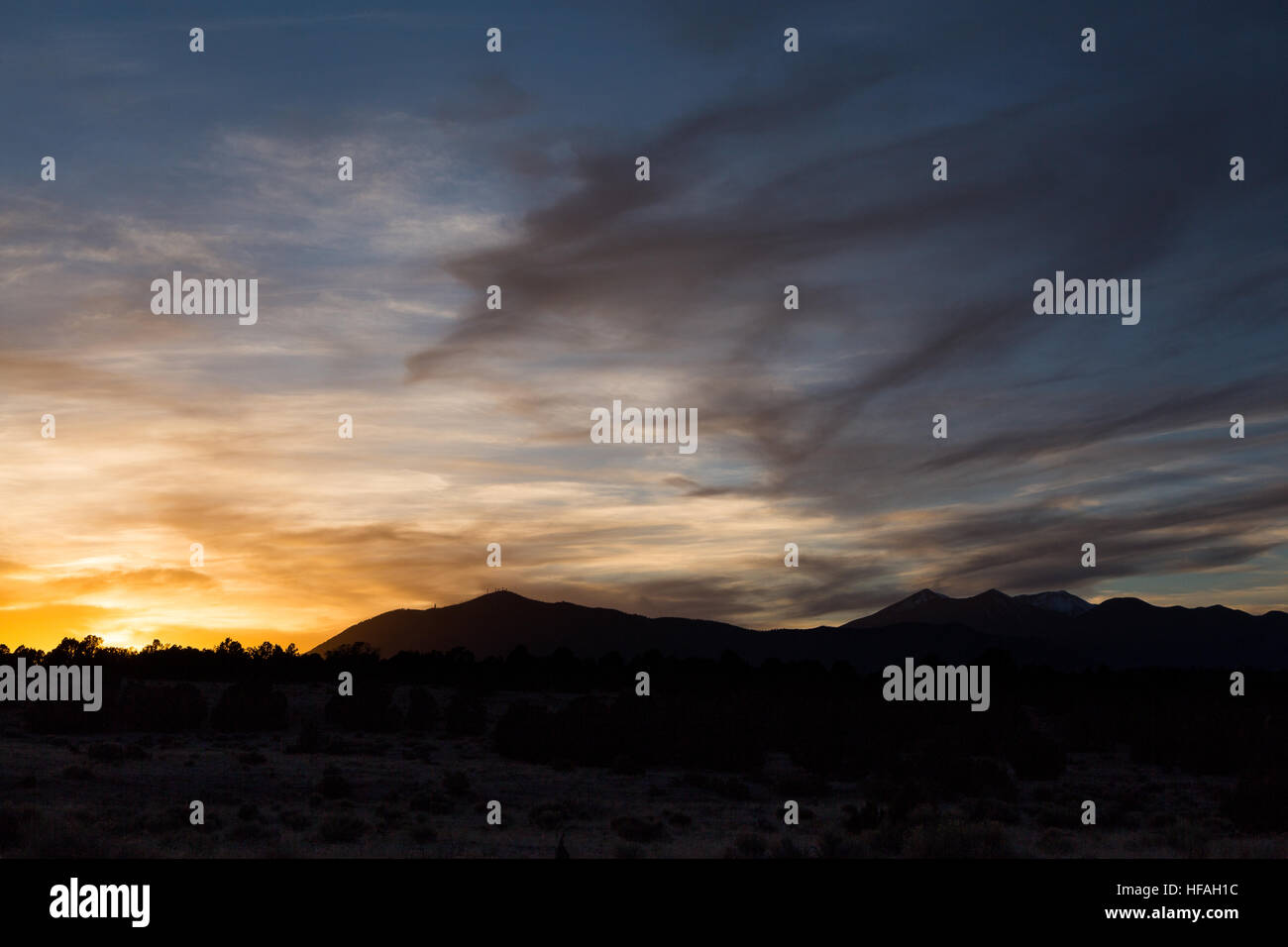 An evening sky lit by sunset silhouetting the San Francisco Peaks ...