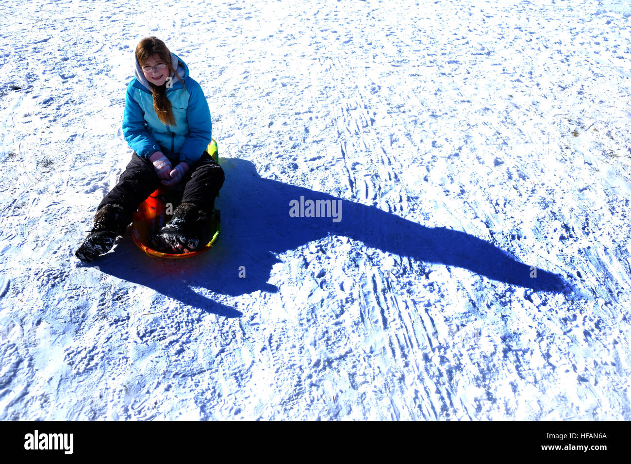 Young girl playing in the snow winter sledding on frozen ground Stock ...