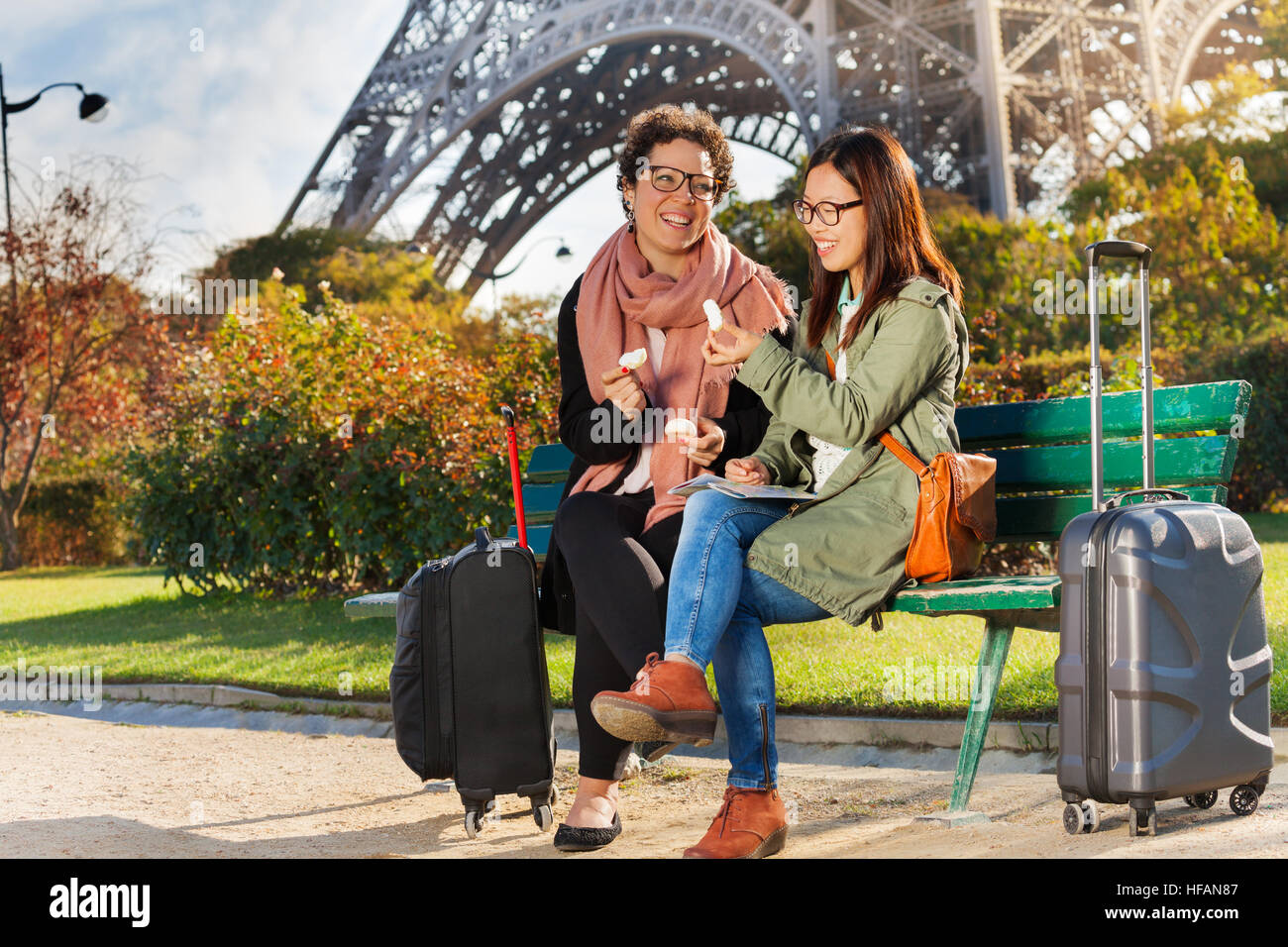 Two travelers tasting macarons sitting on a bench Stock Photo - Alamy