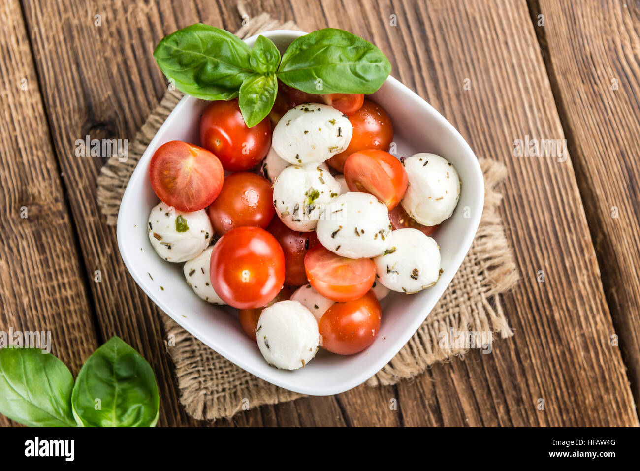 Portion of Mozzarella with Tomatoes on an old wooden table (selective ...