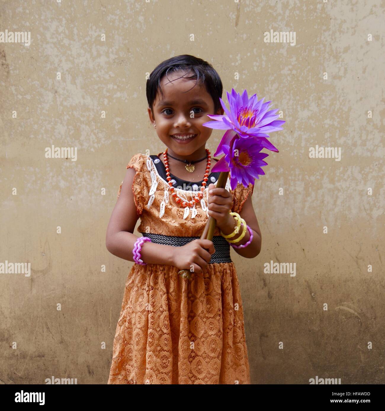 A young Sri Lankan girl wearing a pretty orange dress and jewellery ...