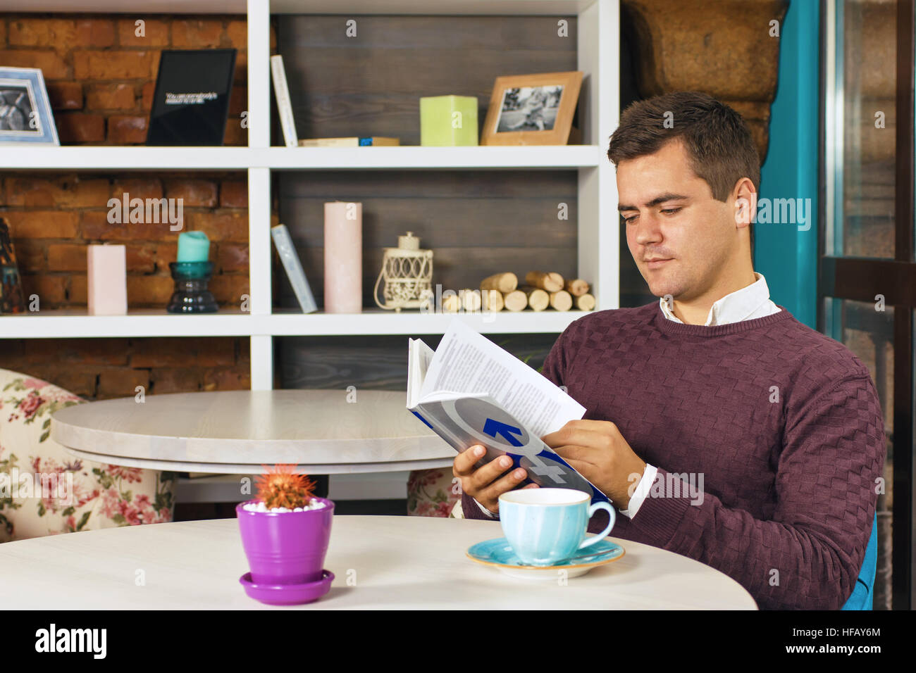 Young man sitting in cafe and reading a book Stock Photo - Alamy