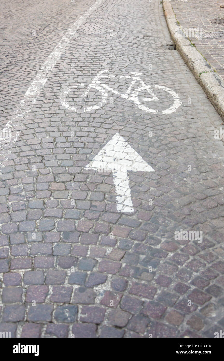White painted signpost with arrow for cyclists on the road. Direction ...
