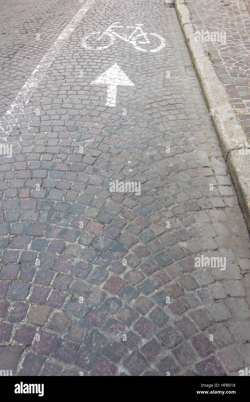 White painted signpost with arrow for cyclists on the road. Direction ...