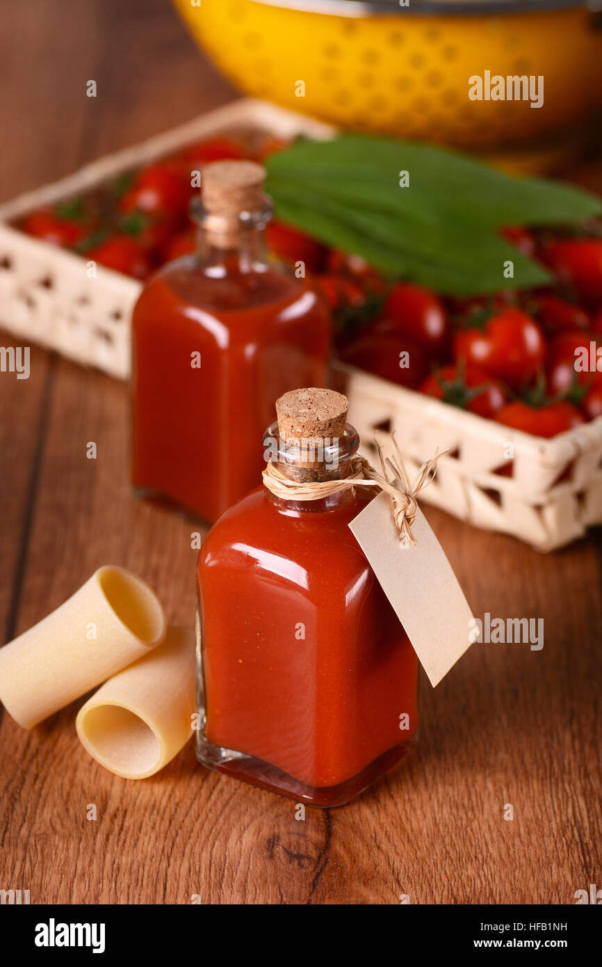 sauce of cherry tomatoes in a glass bottle with ingredients around ...