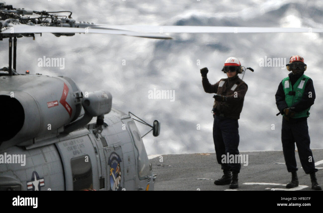 A plane captain signals a MH-60R Seahawk helicopter assigned to ...