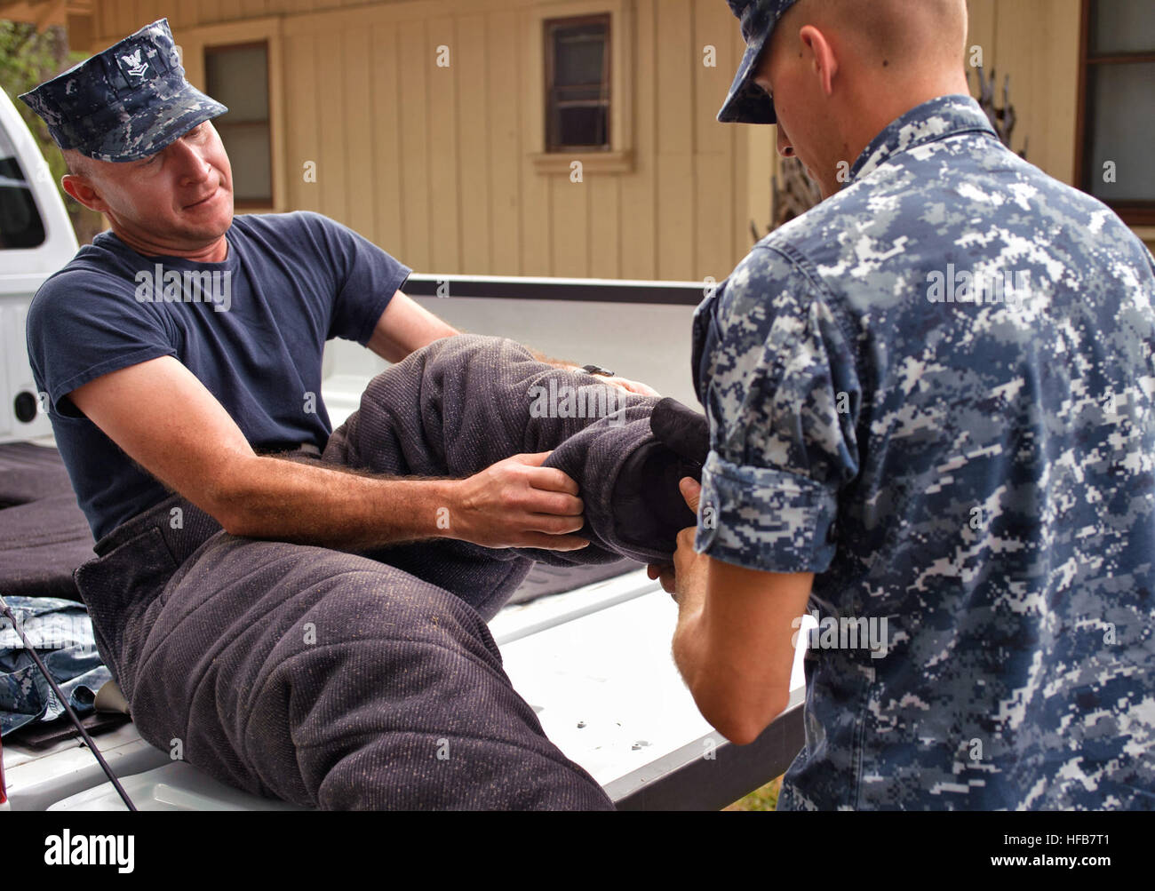 U.S. Navy Master-At-Arms 2nd Class Luke Ross, left, puts on a bite suit ...