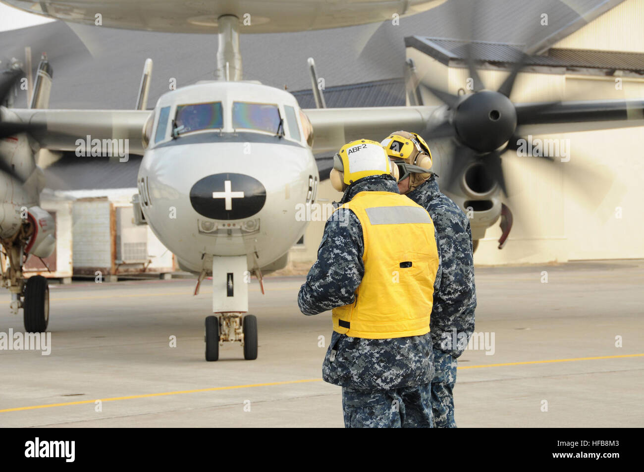 Two aviation flight handlers assist an E-2 Hawkeye park on the Navy ...