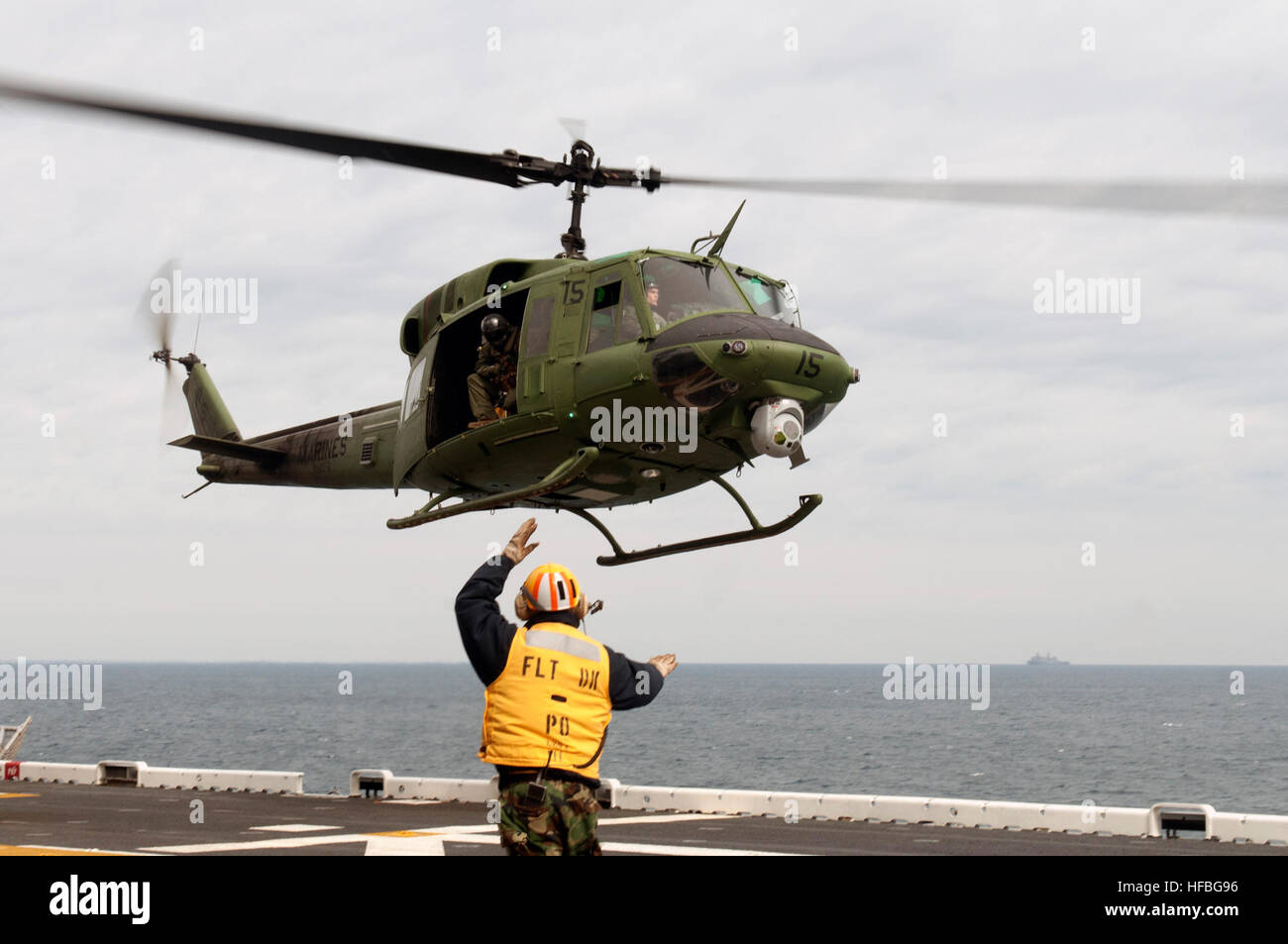 An aviation boatswain's mate directs the takeoff of a UH-1N Huey ...