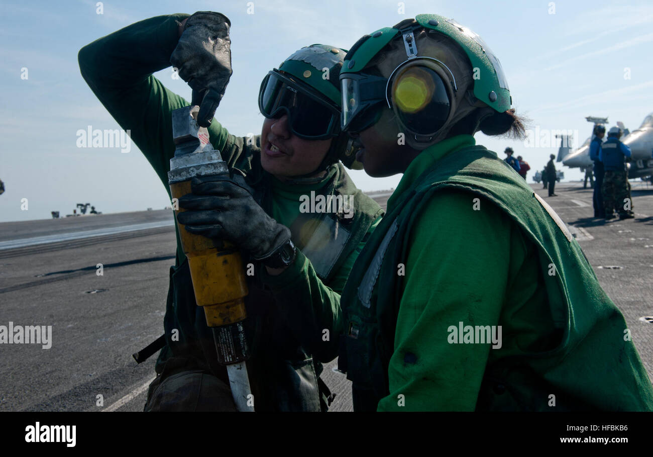 Sailors inspect and check hold back bars on the flight deck of USS John ...